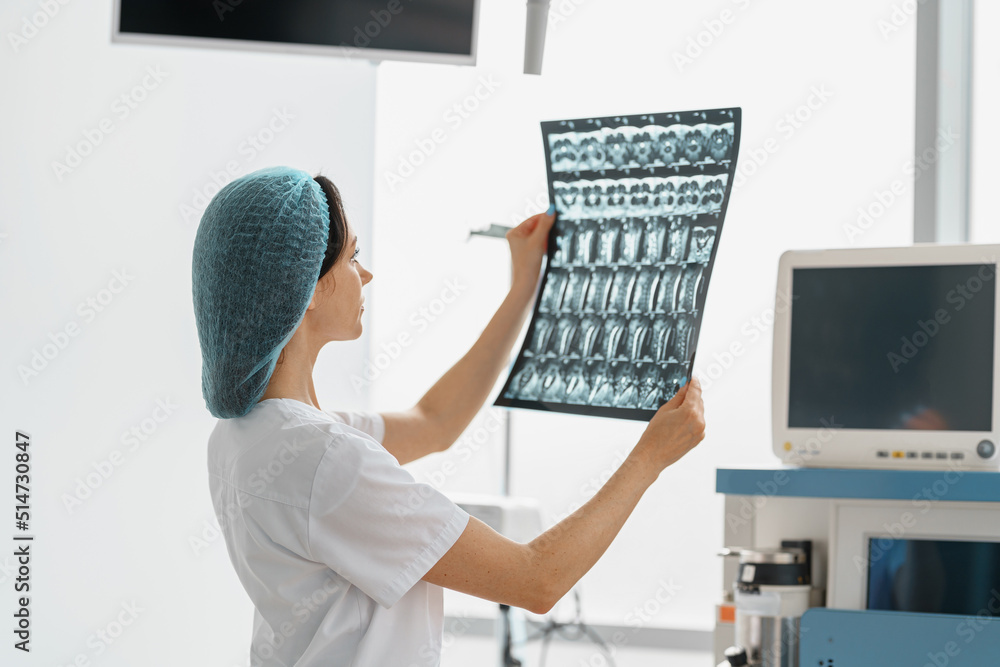 Nurse in uniform look on X-ray or MRI scan of the patient spine in ...
