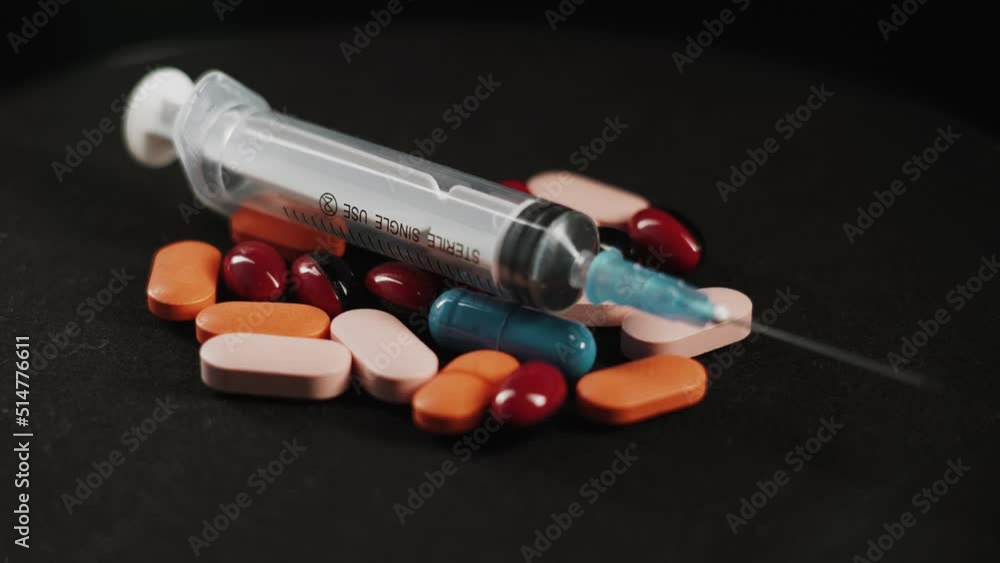 Pills and a syringe with a drug revolve on a black background. the ...