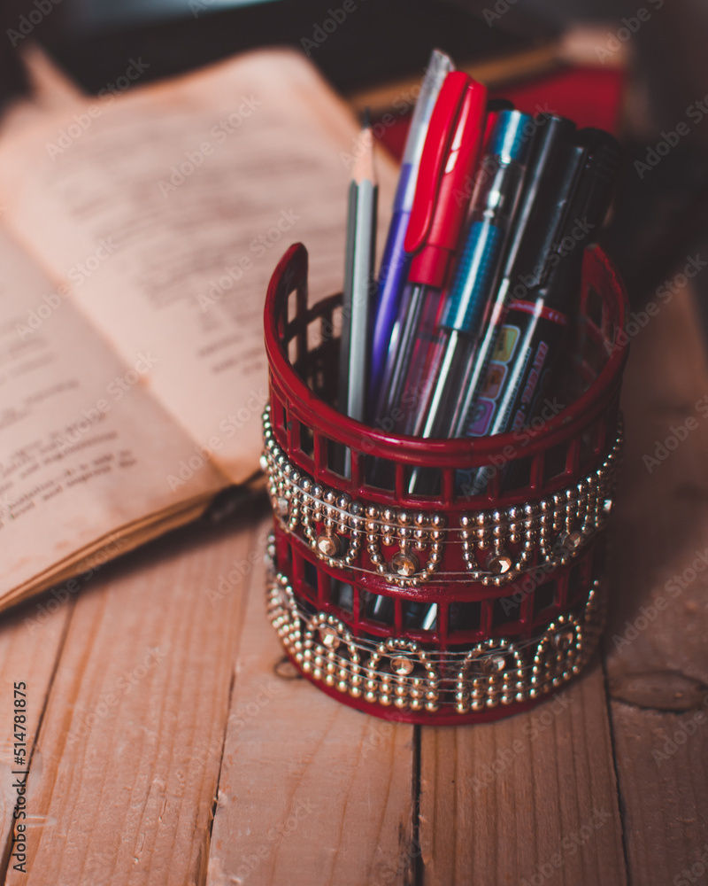 Pen stand on study table with open book Stock Photo | Adobe Stock