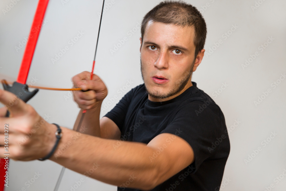 Young boy using a toy bow. The bow is red and the arrow is orange ...