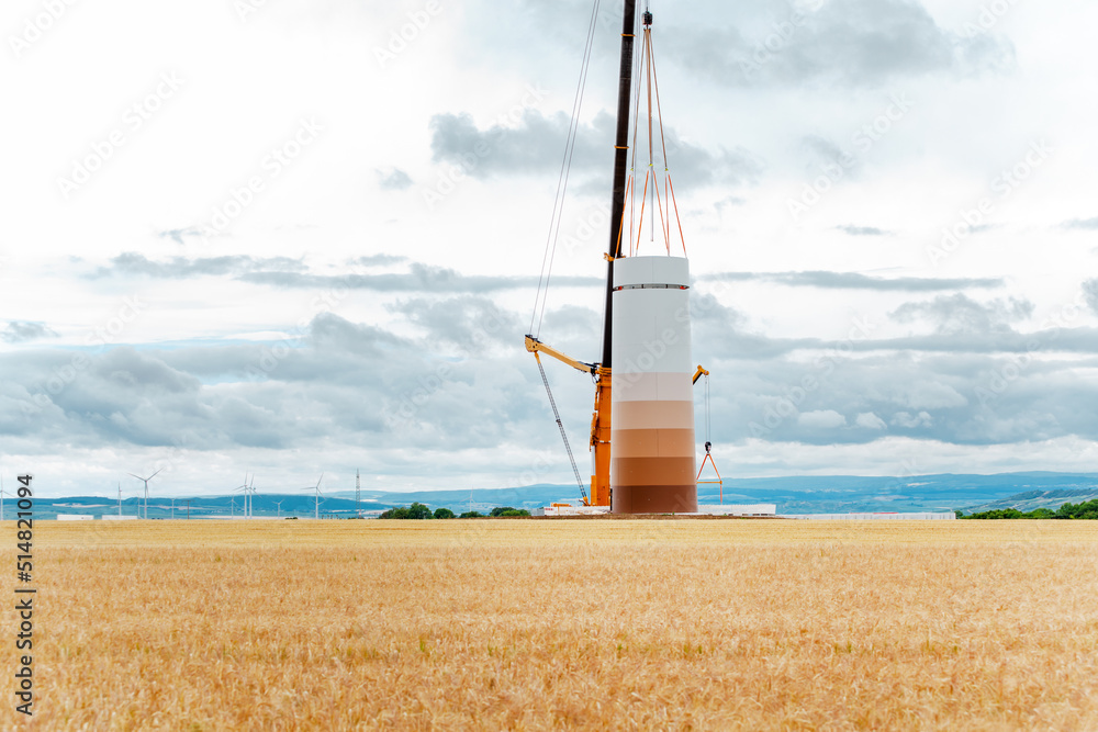 Building and assembling a construction windmill by crane. Farmland with ...