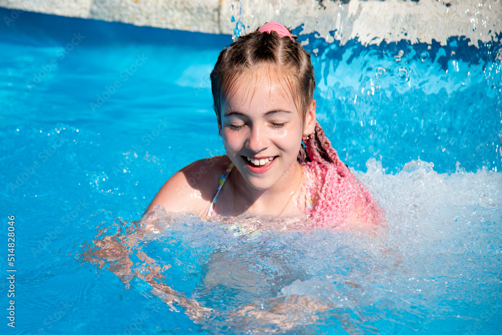 A teenage girl of 11-13 years old swims in a pool with blue water. She ...