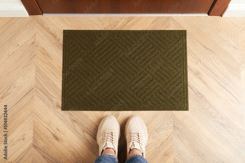 Woman standing near door mat on wooden floor in hall, top view Stock ...