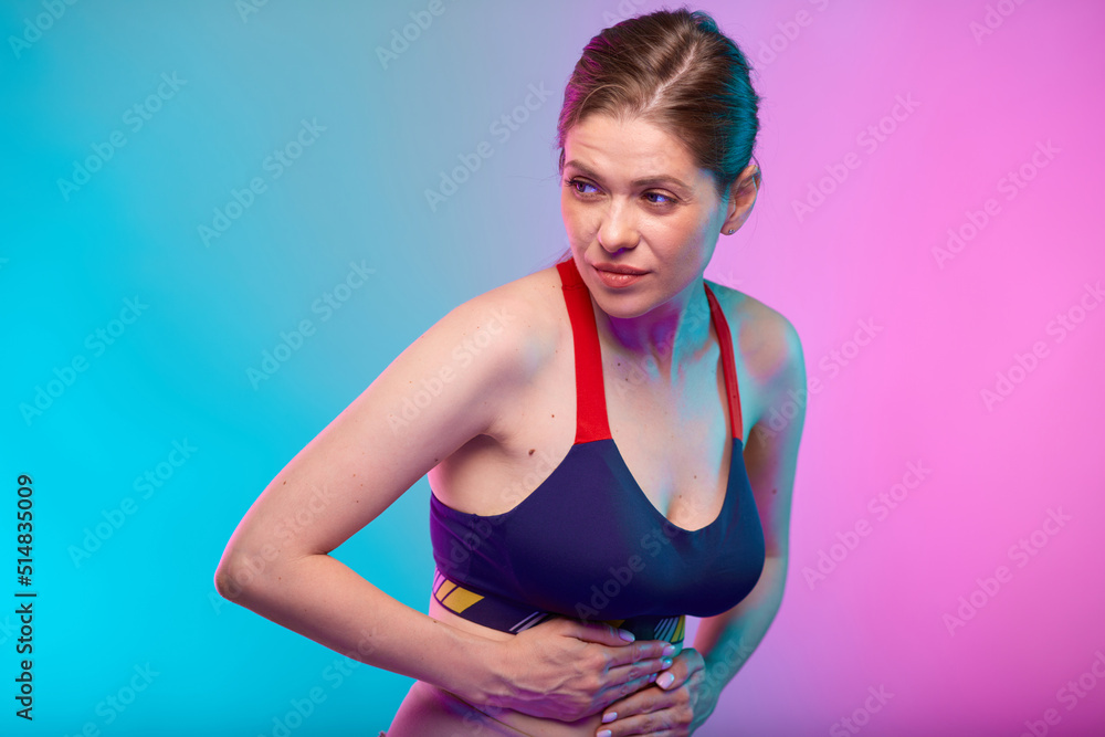 Woman looking back over shoulder, hand on stomach, abdominal pain and ...