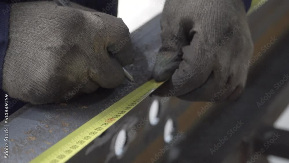 A man (worker/builder) makes a tick/mark on the metal with a tape ...