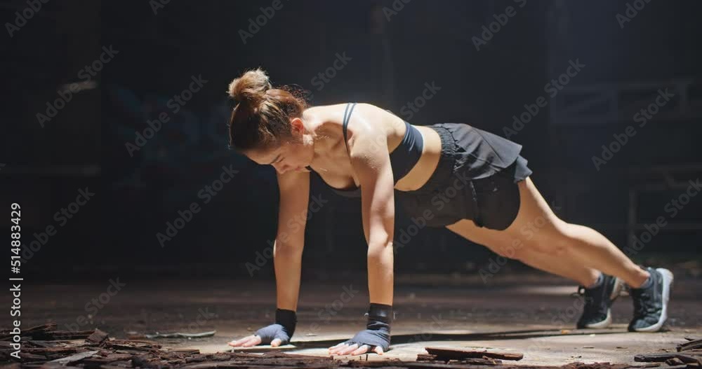 Young asian female boxer doing push ups exercises in abandoned building ...