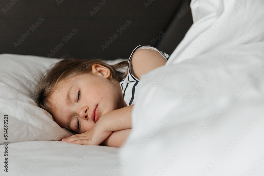 The little girl went to bed for a nap in her parents' bed. Portrait of ...