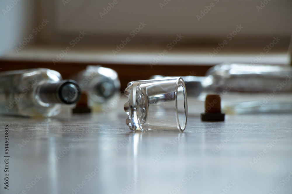 A glass and empty alcohol bottles lie on the floor in an apartment in ...