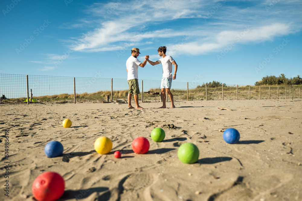 Tourists play an active game, petanque on a sandy beach by the sea ...