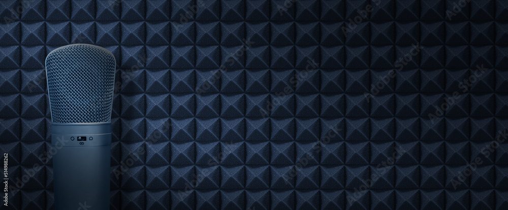 Vocal microphone with dark acoustic foam background in recording studio ...