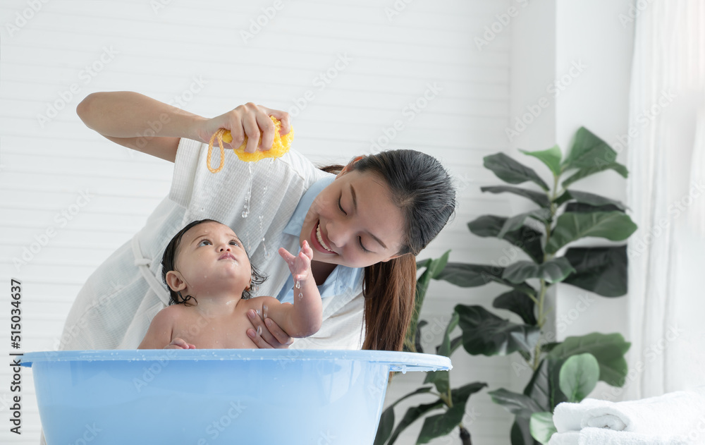Asian little baby bathing in bathtub and looking at sponge which young ...