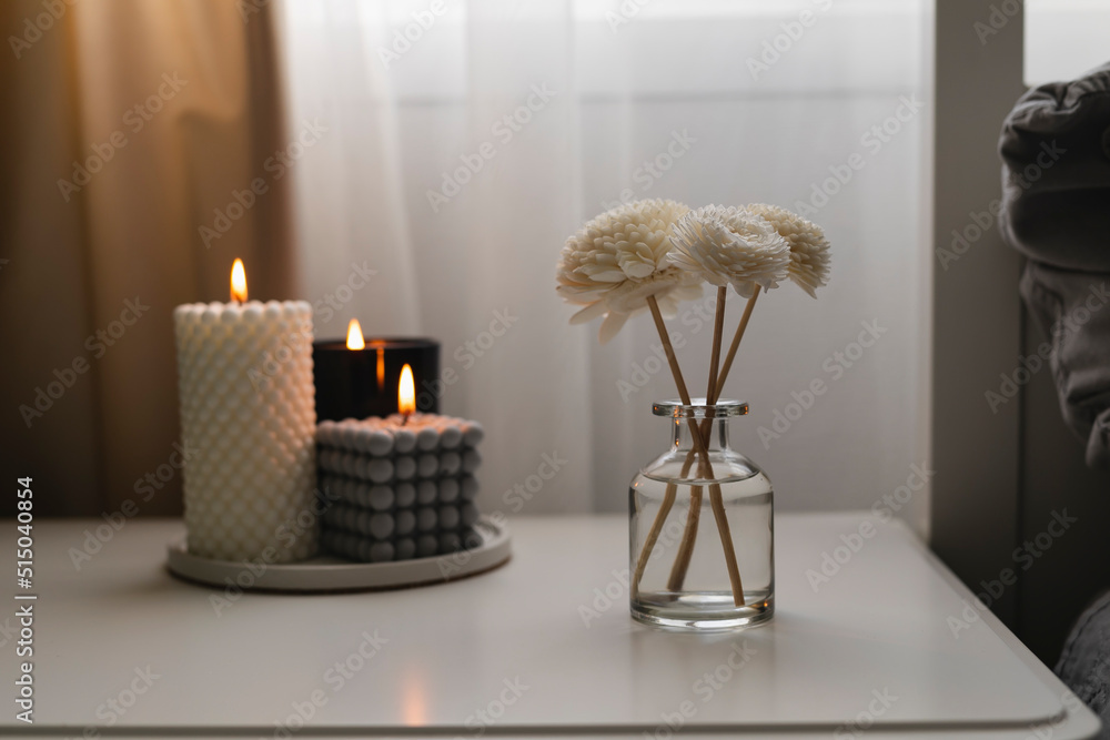Home aroma fragrance diffuser and burning candles on bedside table in ...