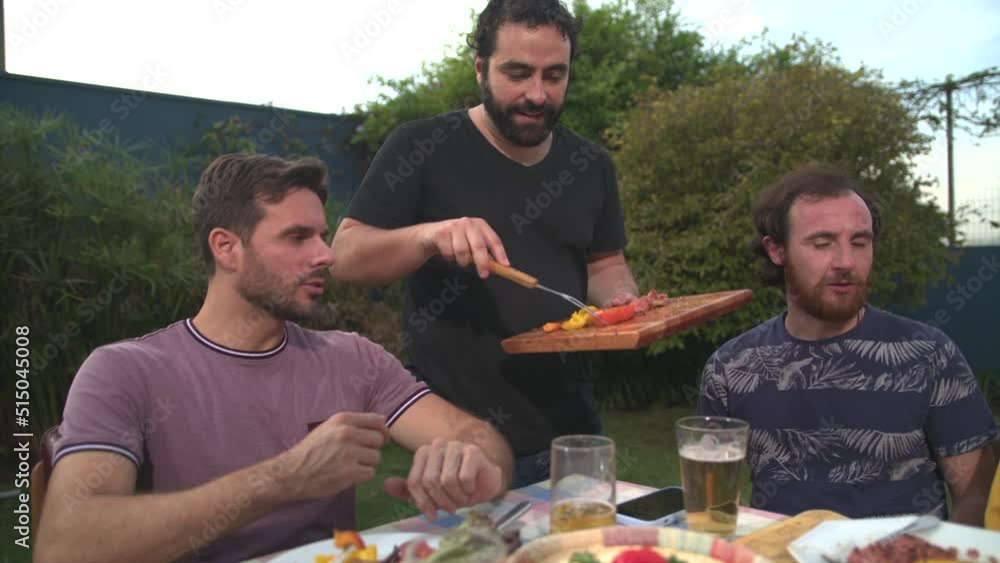 Group of cheerful friends eating barbecue together. BBQ chef serving ...