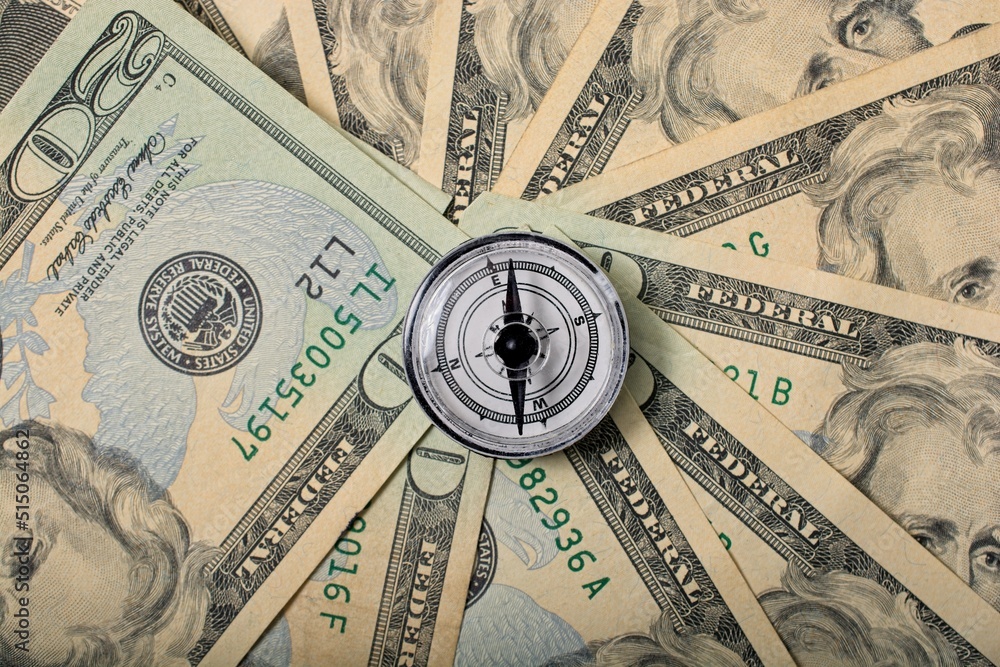 'Compass set on top of spiral of American twenty dollar bills.' foto de Stock | Adobe Stock