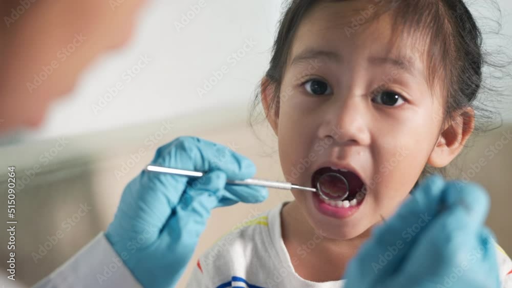 Dental kid health examination. Doctor examines oral cavity of little child uses mouth mirror to ...