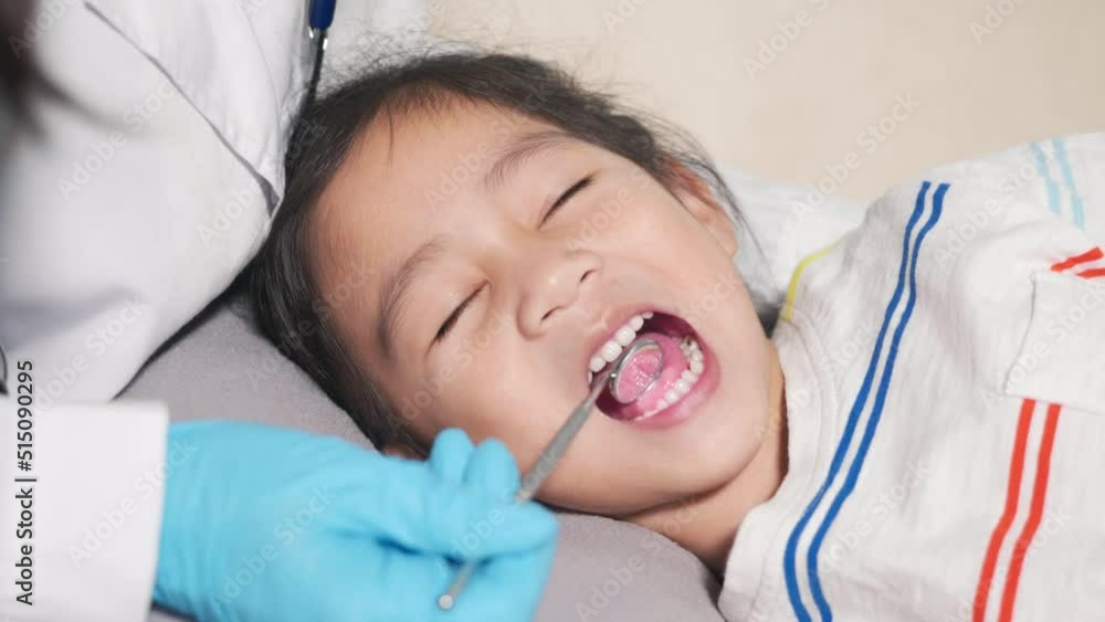 Dental kid health examination. Asian dentist making examination procedure for cute little girl ...