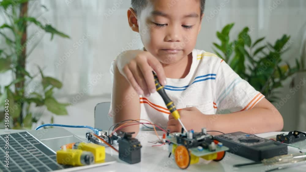 Vidéo Stock Asian kid boy assembling the Arduino robot car homework ...