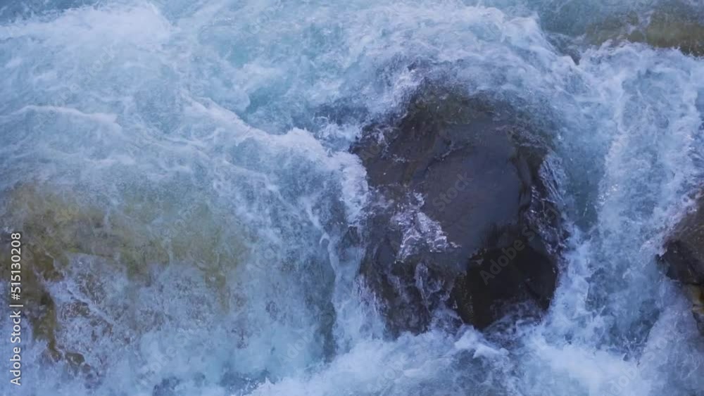 Closeup slow motion shot of a rock obstructing the flow of the river ...