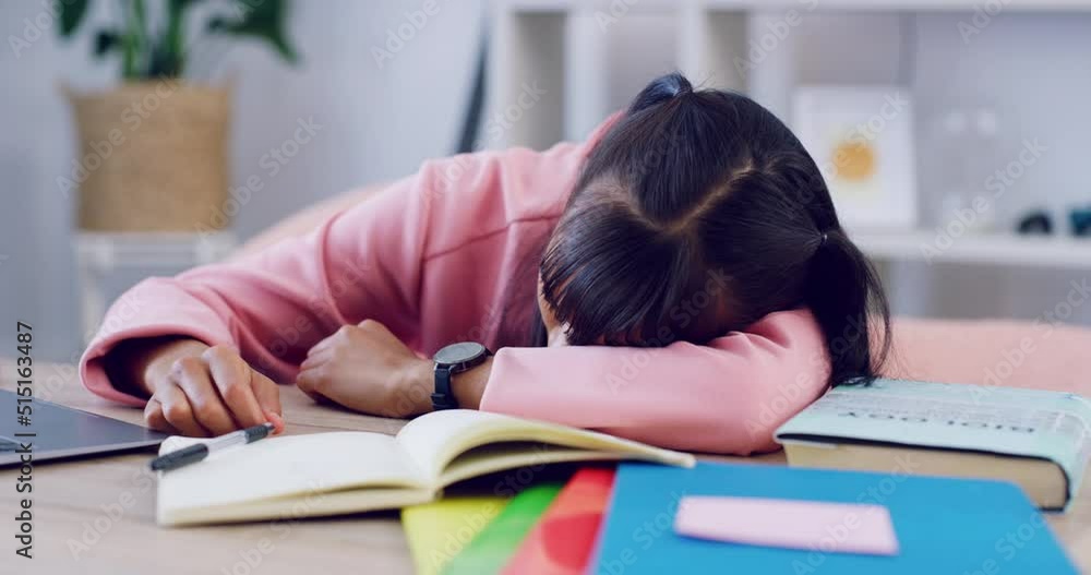 Tired student sleeping at her desk while studying for university or ...