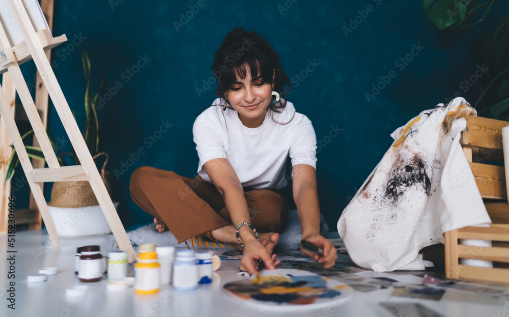 Attractive young female artist draws picture with paints and enjoys ...