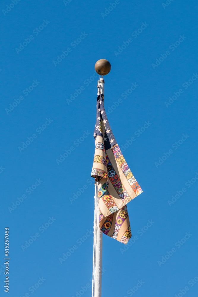 A peace flag with peace symbols sewed to a light tan background material. White stars with a ...