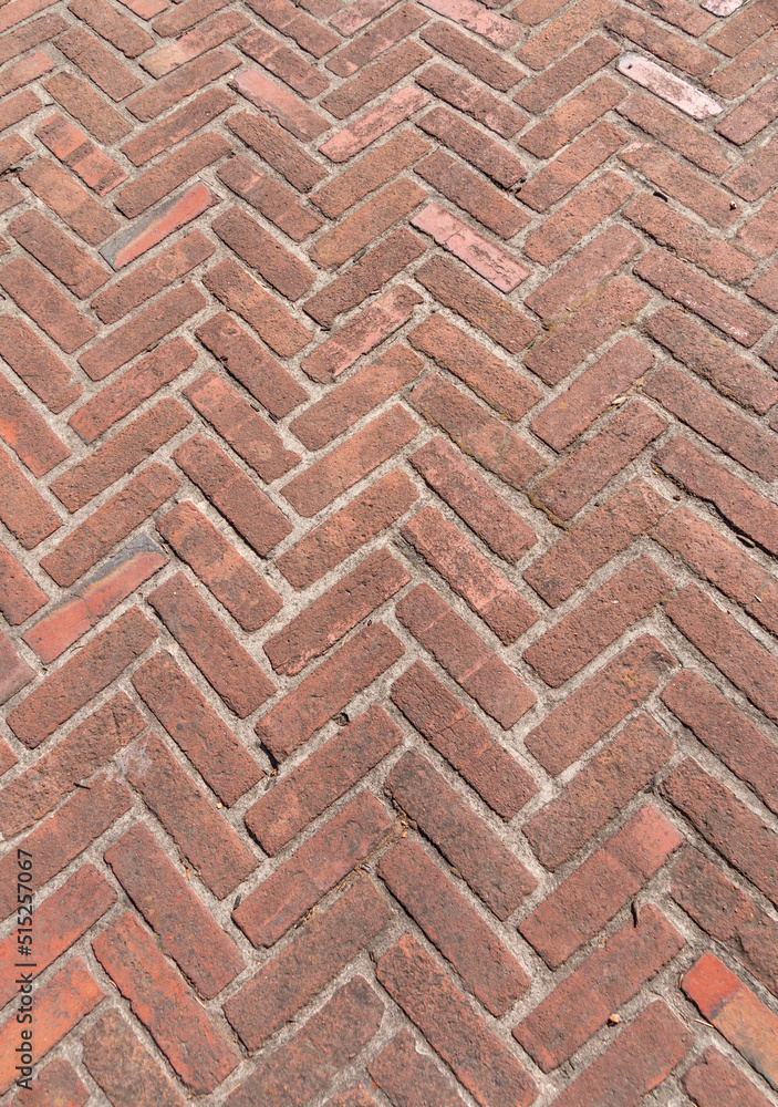 Old red brick set in a triangle pattern. There is white mortar between ...