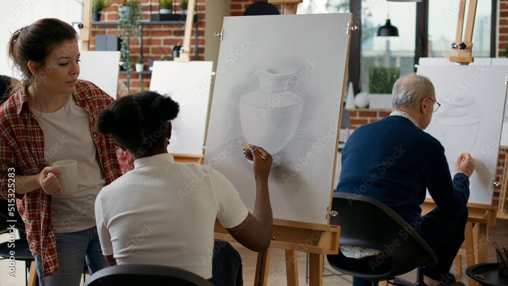 Foto de Teacher explaining to young woman how to draw vase model on ...