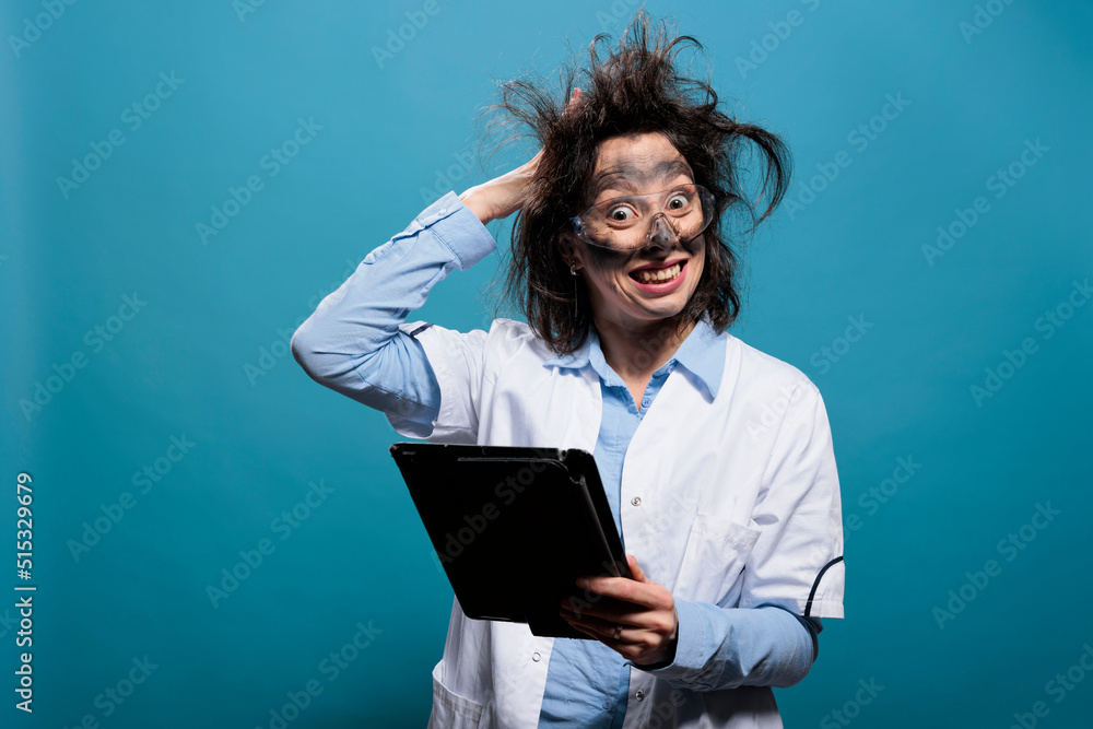 Nutcase biochemist with messy hair and dirty face having tablet looking ...
