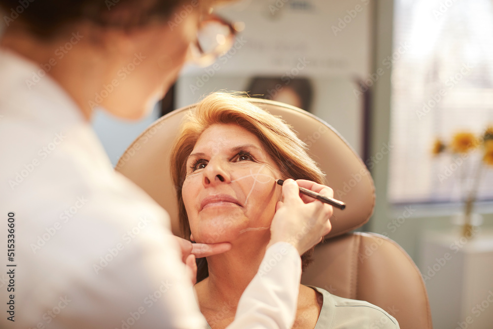 Female doctor drawing correction lines on woman's face Stock Photo ...