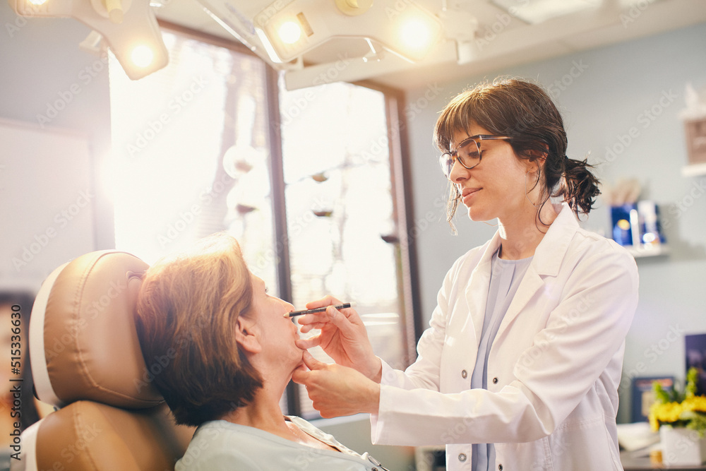 Female doctor drawing correction lines on woman's face Stock Photo ...