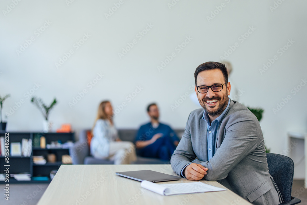 Adult businessman holding hands on the desk, smiling for the camera ...
