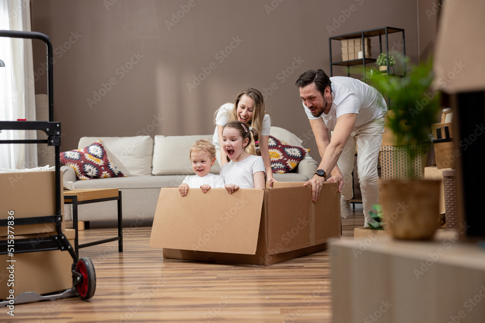 Parents playing with children in living room of new apartment, sweet ...