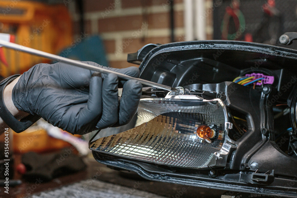 Car headlight in repair close-up. The car mechanic installs the lens in ...
