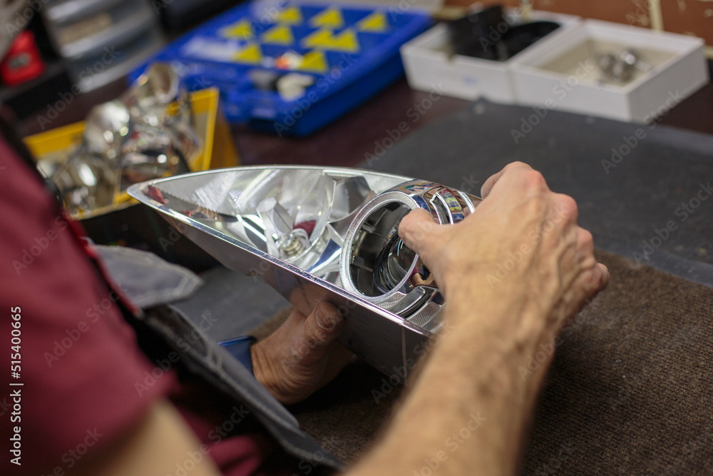 Car headlight in repair close-up. The car mechanic installs the lens in ...