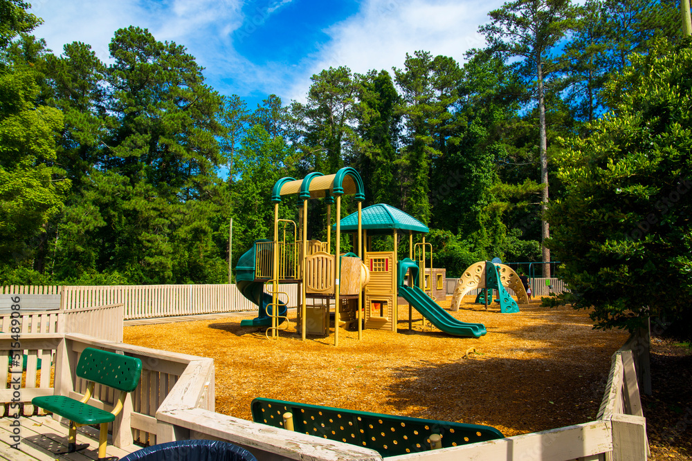 a brown and green jungle gym on a playground surrounded by lush green ...