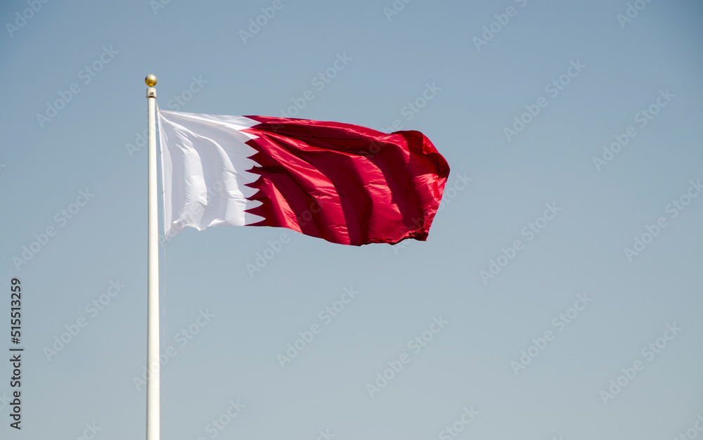 The national flag of Qatar. It is maroon with a broad white serrated ...