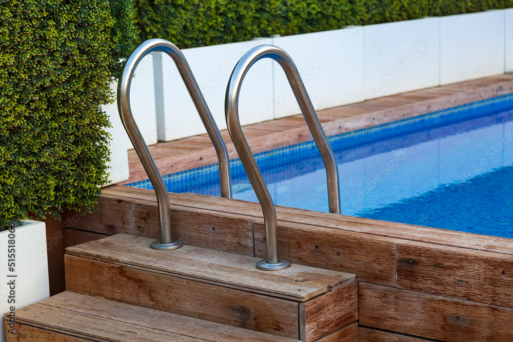 Wooden steps into the pool with metal handrails. The planking of a ...