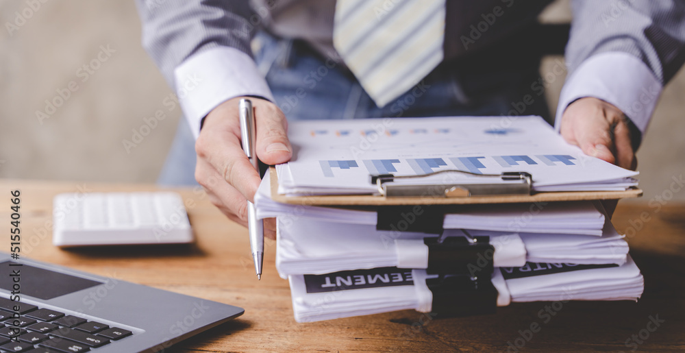 work from office A businessman works a bunch of paper files to find ...