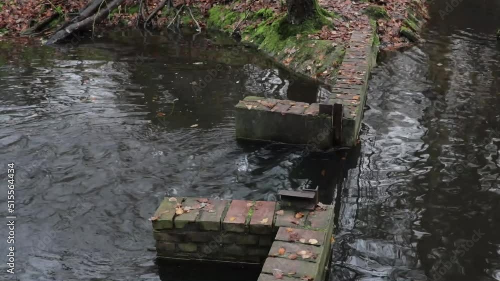 Water passing through a small passage between two brick walls. Filmed ...