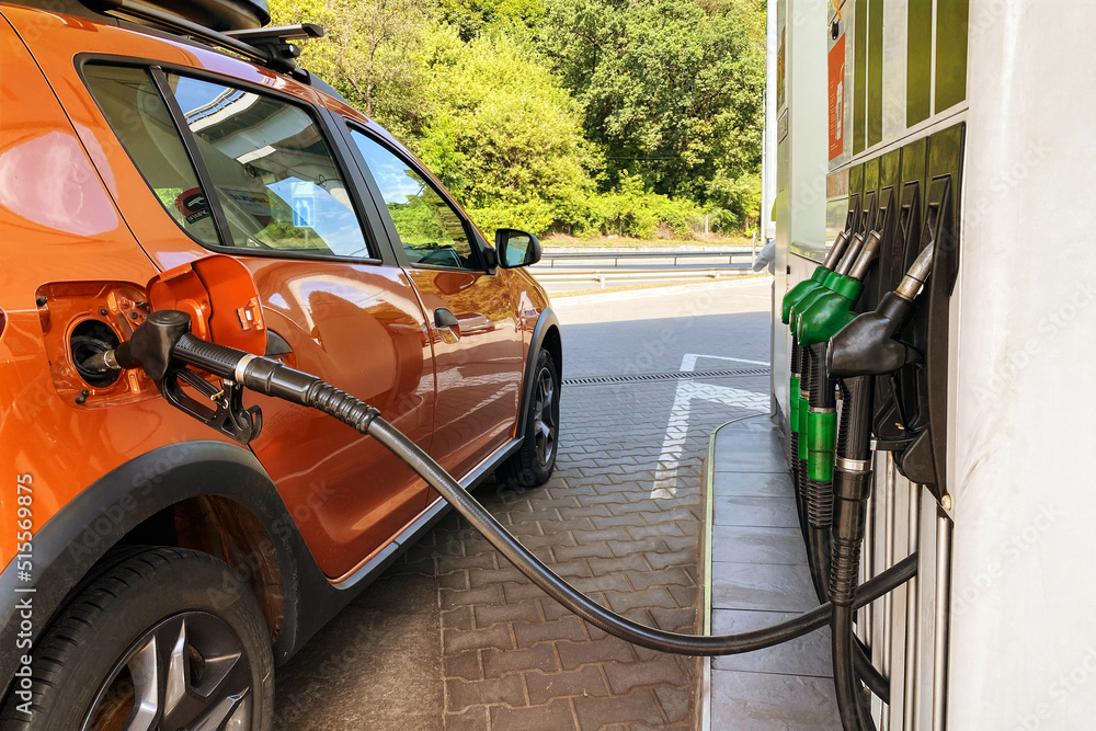 Pumping gasoline fuel in orange car at a gas station. Fill car with ...