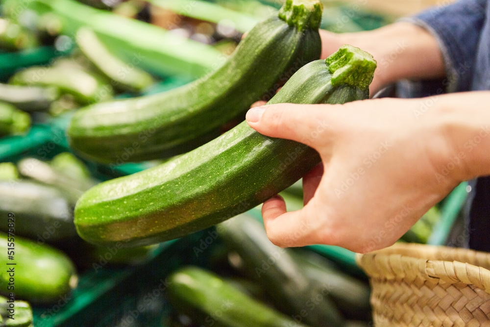 Hands of a customer with two zucchini while shopping Stock Photo ...