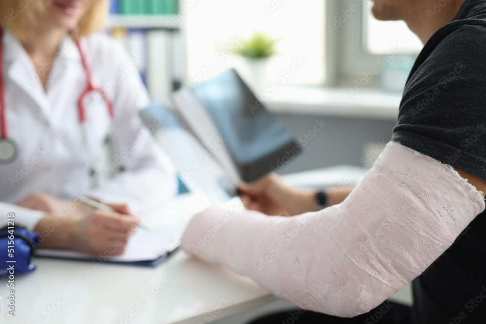Doctor conducts medical consultation with patient with cast on arm ...