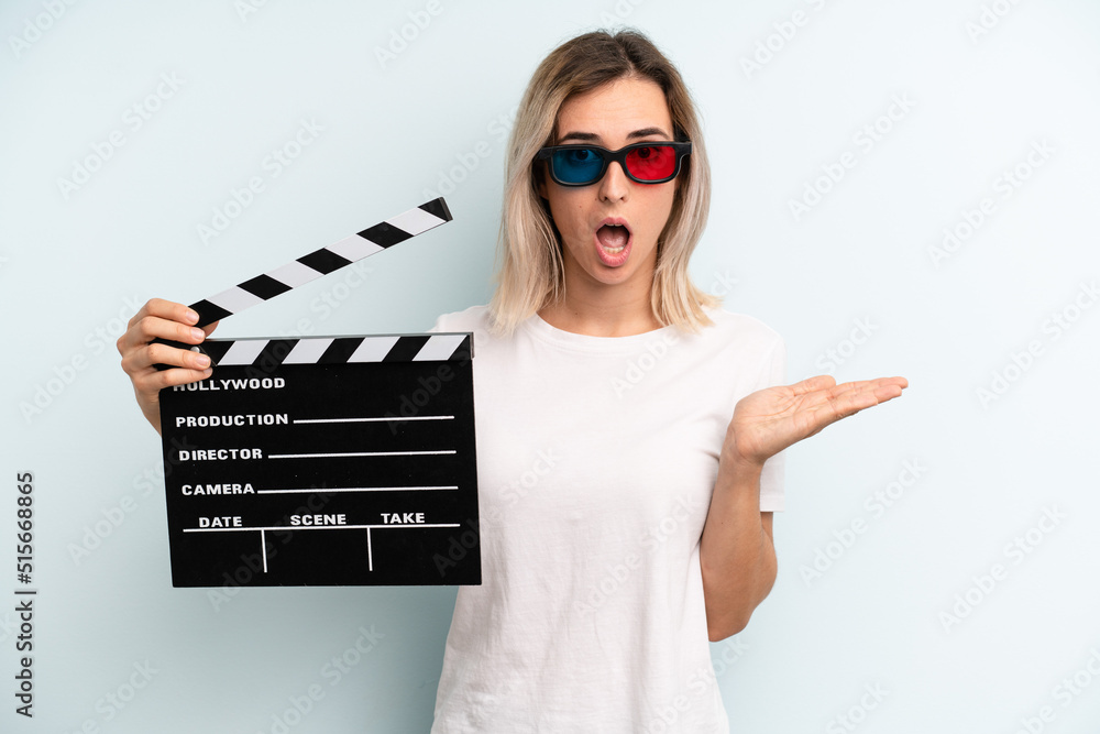 blonde woman looking surprised and shocked, with jaw dropped holding an ...