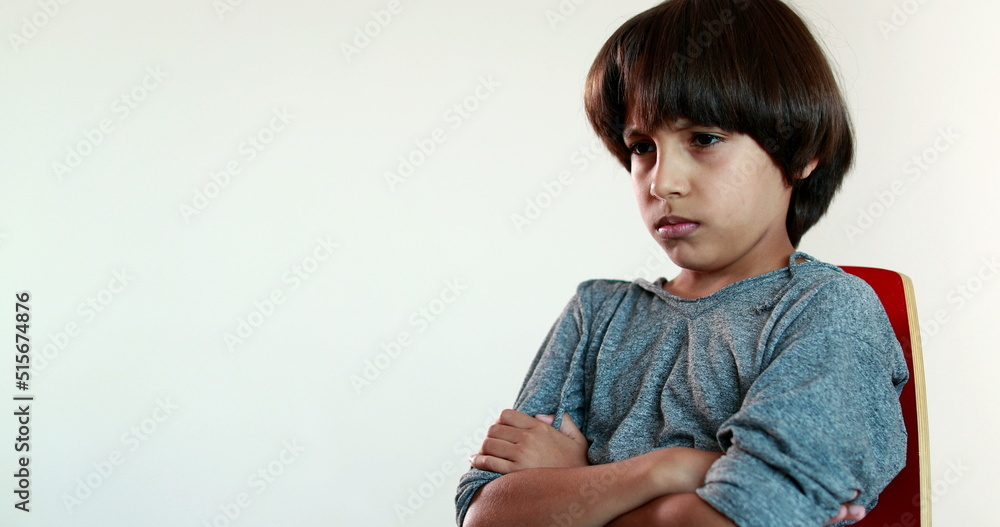 Upset young boy of mixed race crossing arms. Angry child with arms ...