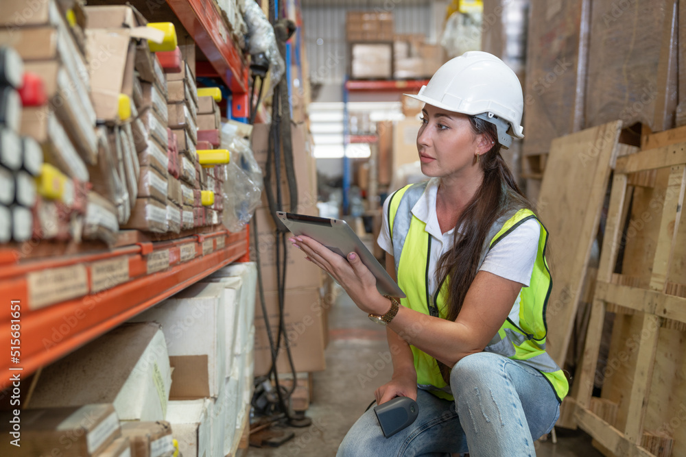 Female employee worker in safety vest and helmet using tablet and ...