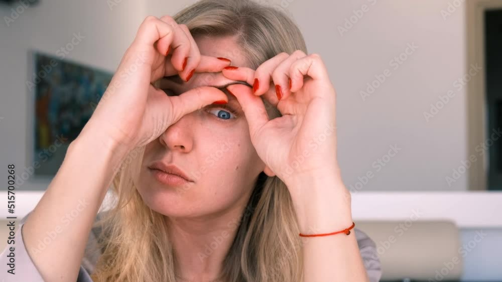 Ageing. Sagging skin. Young woman does facelift exercises by looking in ...