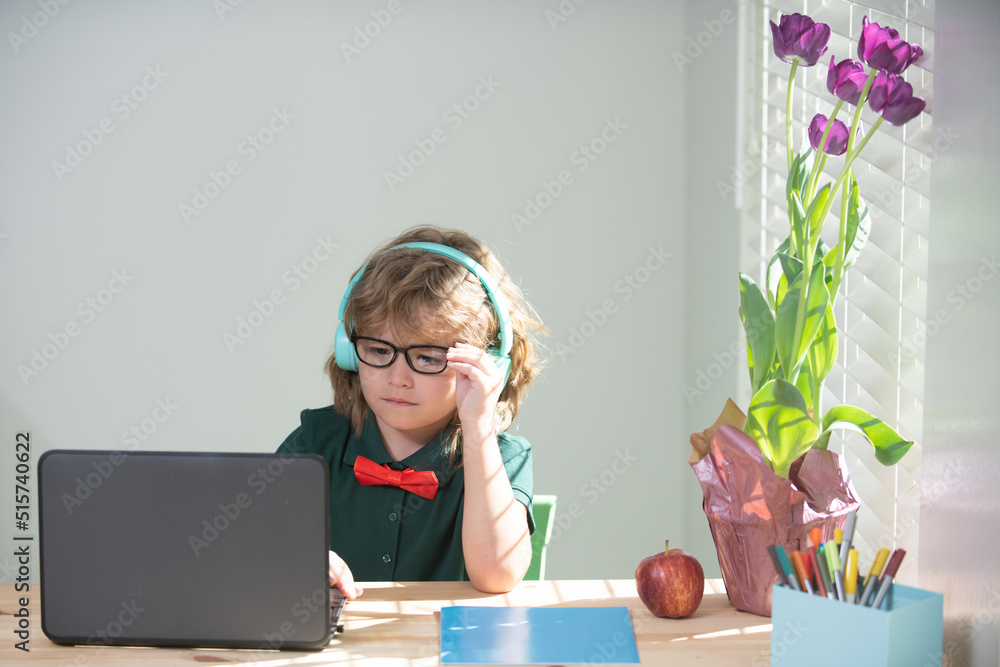 School boy doing her homework with laptop. Child using gadgets to study ...