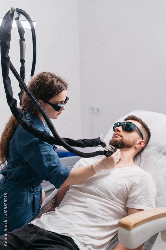 Laser depilation of beard contour. The depilation master treats the ...