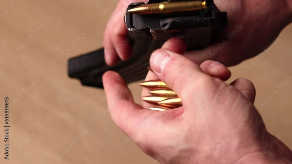 Male hands loading Kalashnikov assault rifle magazine with cartridges ...