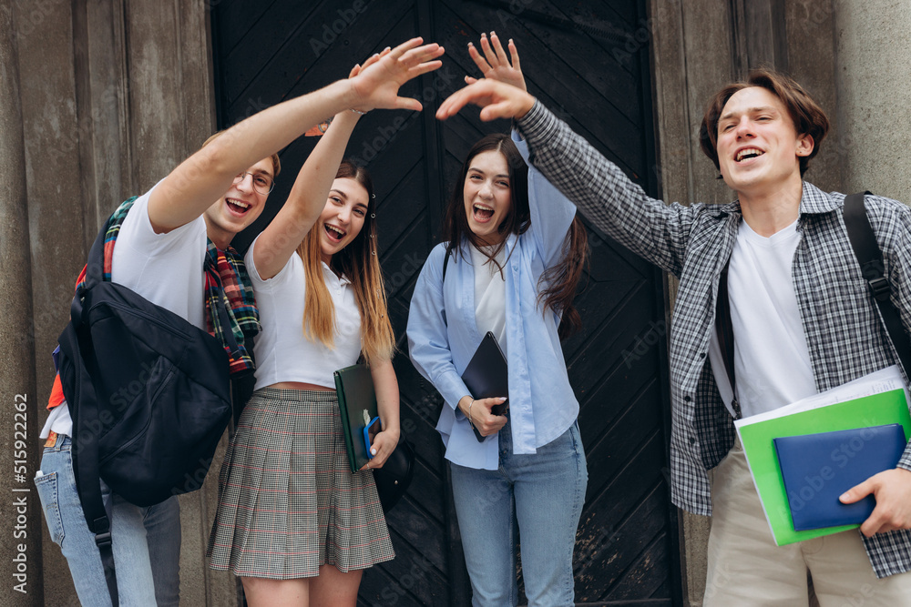 Group of students standing in a circle with hands raised in the air ...